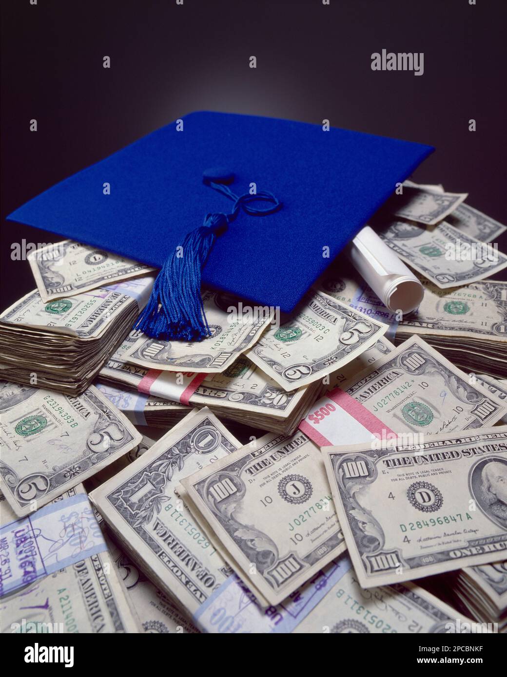 Symbolic, still life of a pile of US currency with a graduation cap and ...