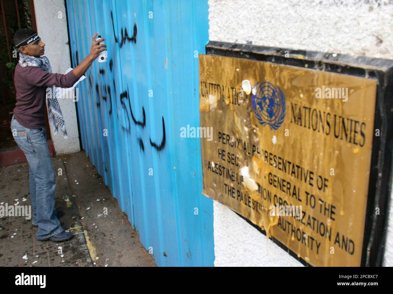 A Palestinian spray paints a door of the United Nations during a ...