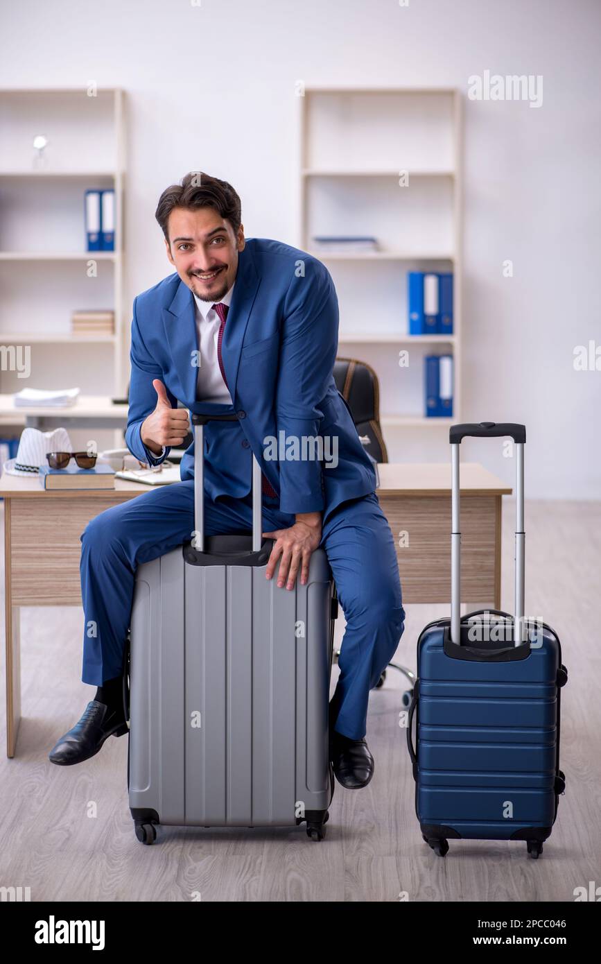 Young businessman employee preparing for trip at workplace Stock Photo ...
