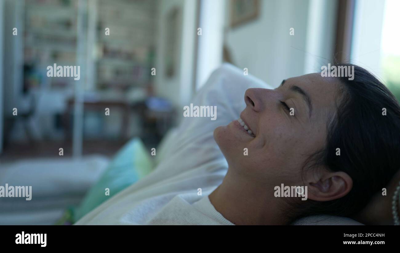 Woman relaxing at home with eyes closed smiling and laughing. Person ...