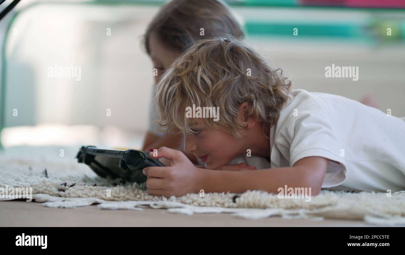 Small kids in front of technology device screen looking at screen lying ...
