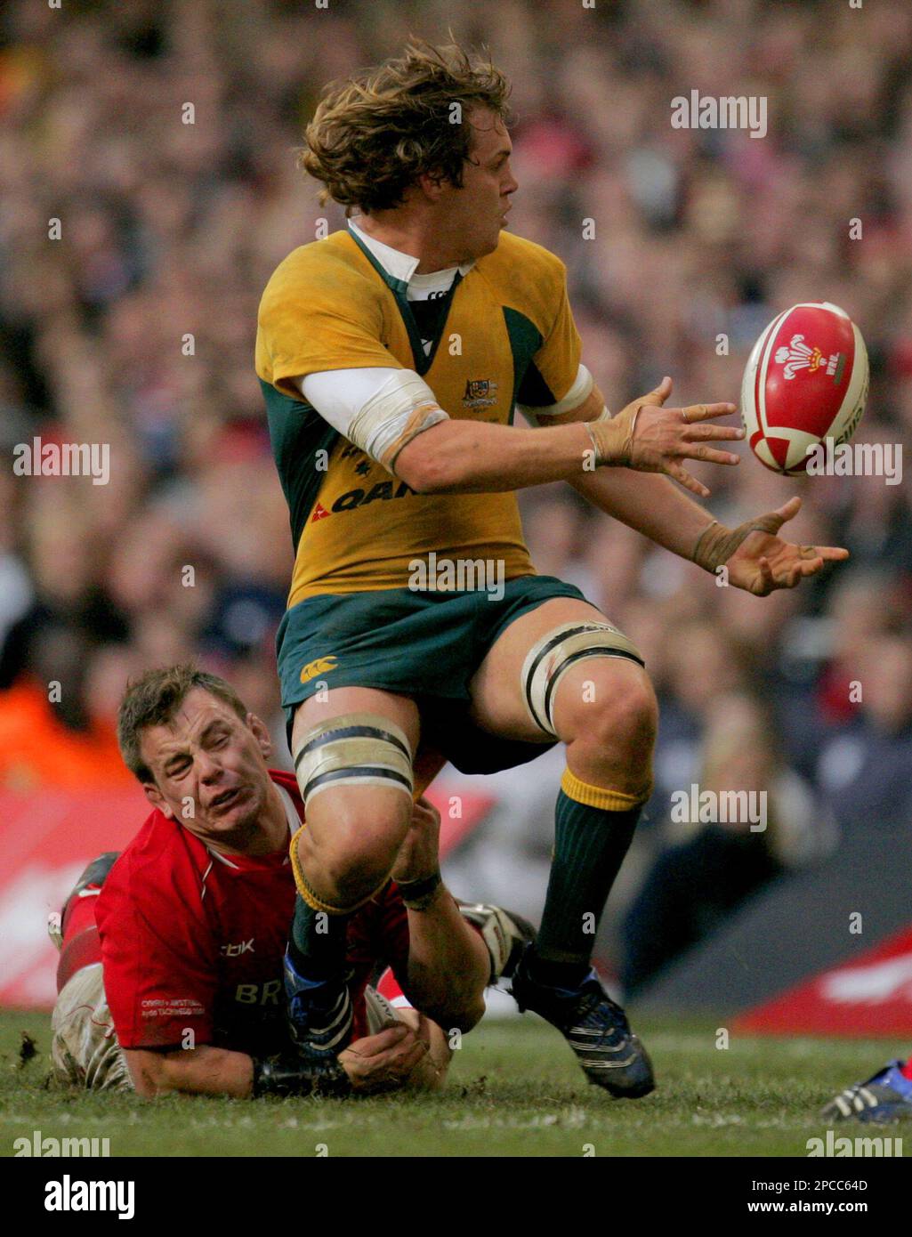 Australia's Rocky Elsom, front, passes the ball as Wales' Mark Jones ...