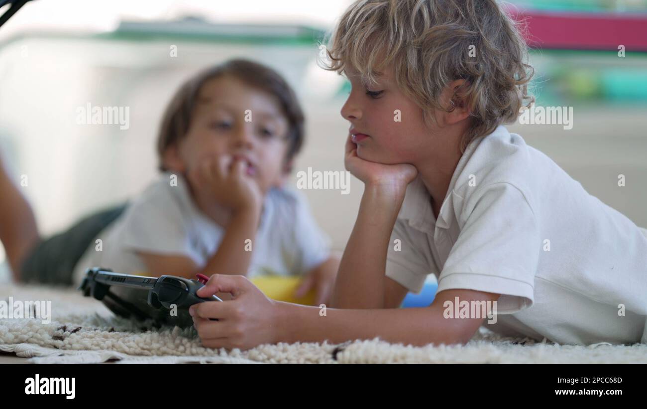 Small kids in front of technology device screen looking at screen lying ...