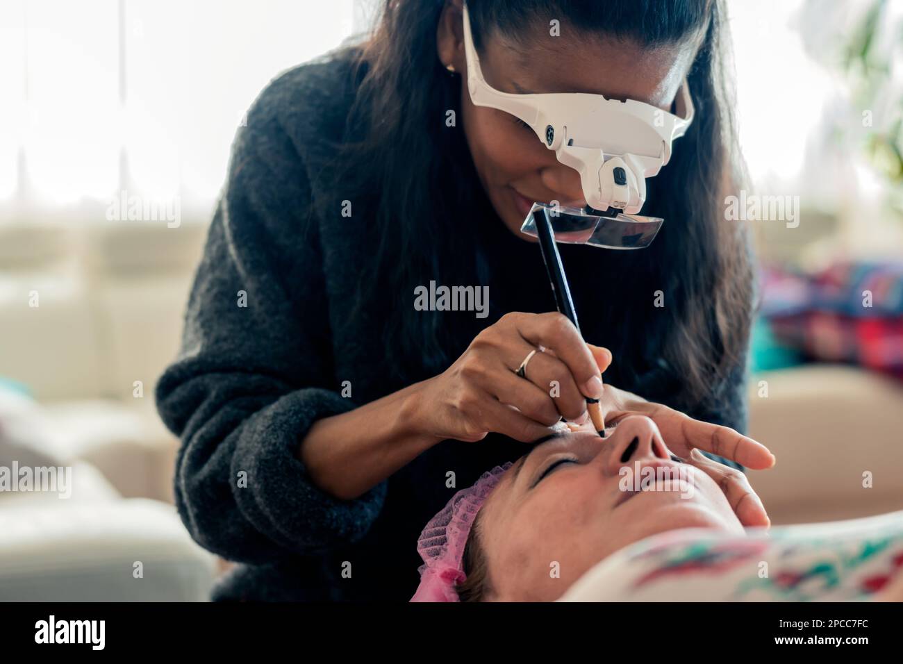 Crop female black microblading master in magnification goggles drawing ...