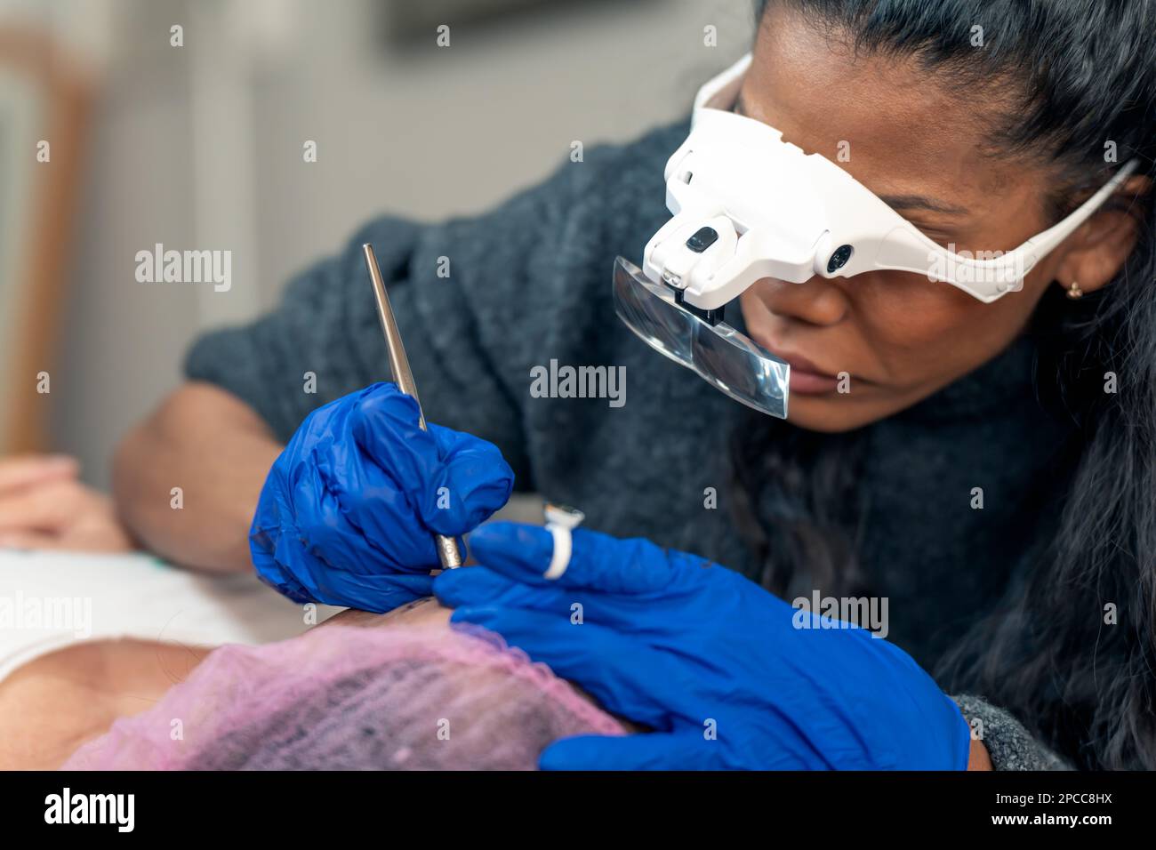Crop female cosmetologist in magnification goggles for microblading ...