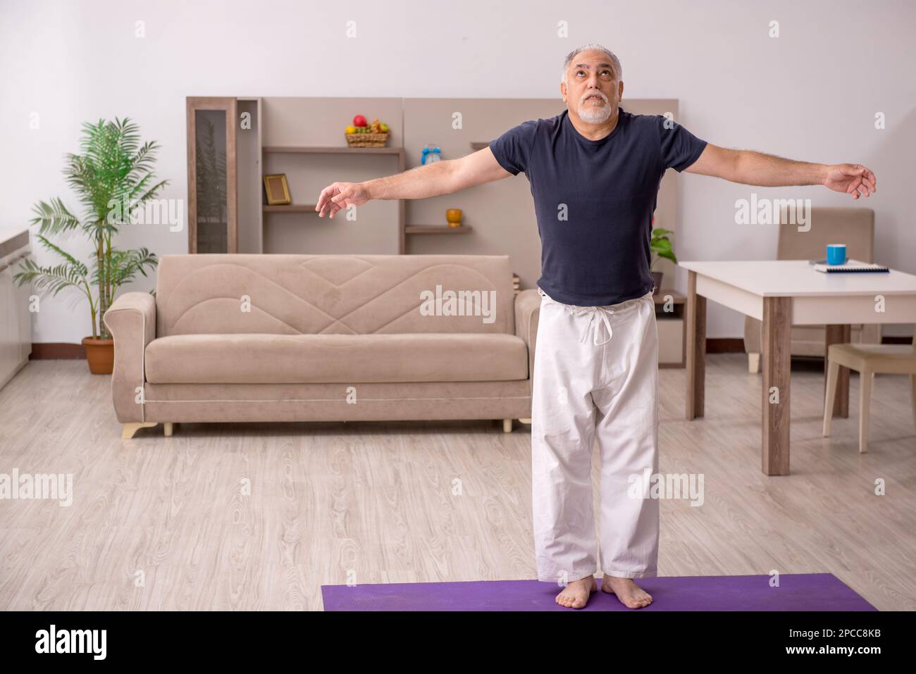 Old man doing sport exercises indoors Stock Photo - Alamy