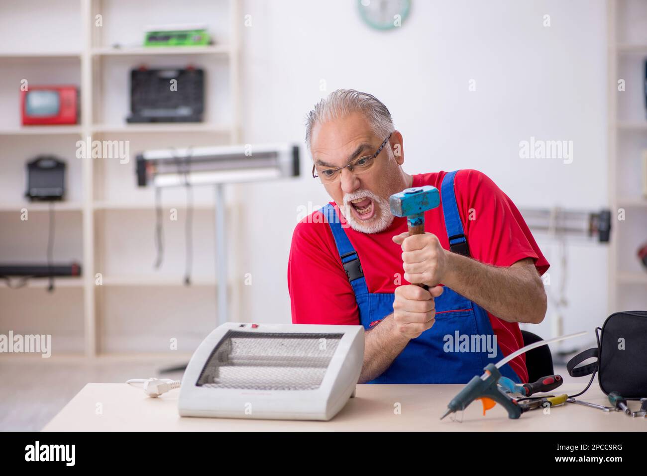 Old male repairman repairing heater at workshop Stock Photo - Alamy