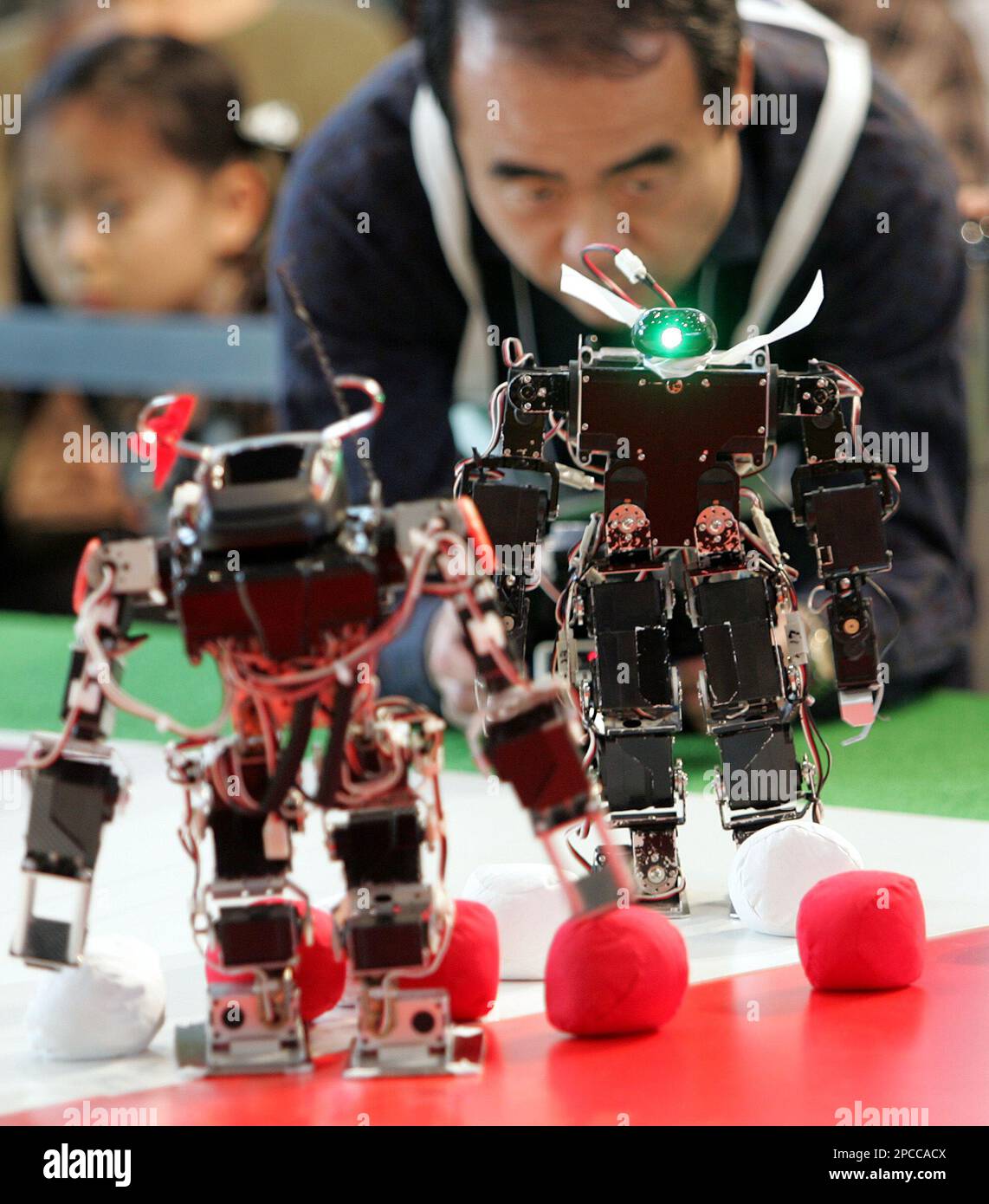 A man concentrates on operating one of the humanoid robots competing in ...