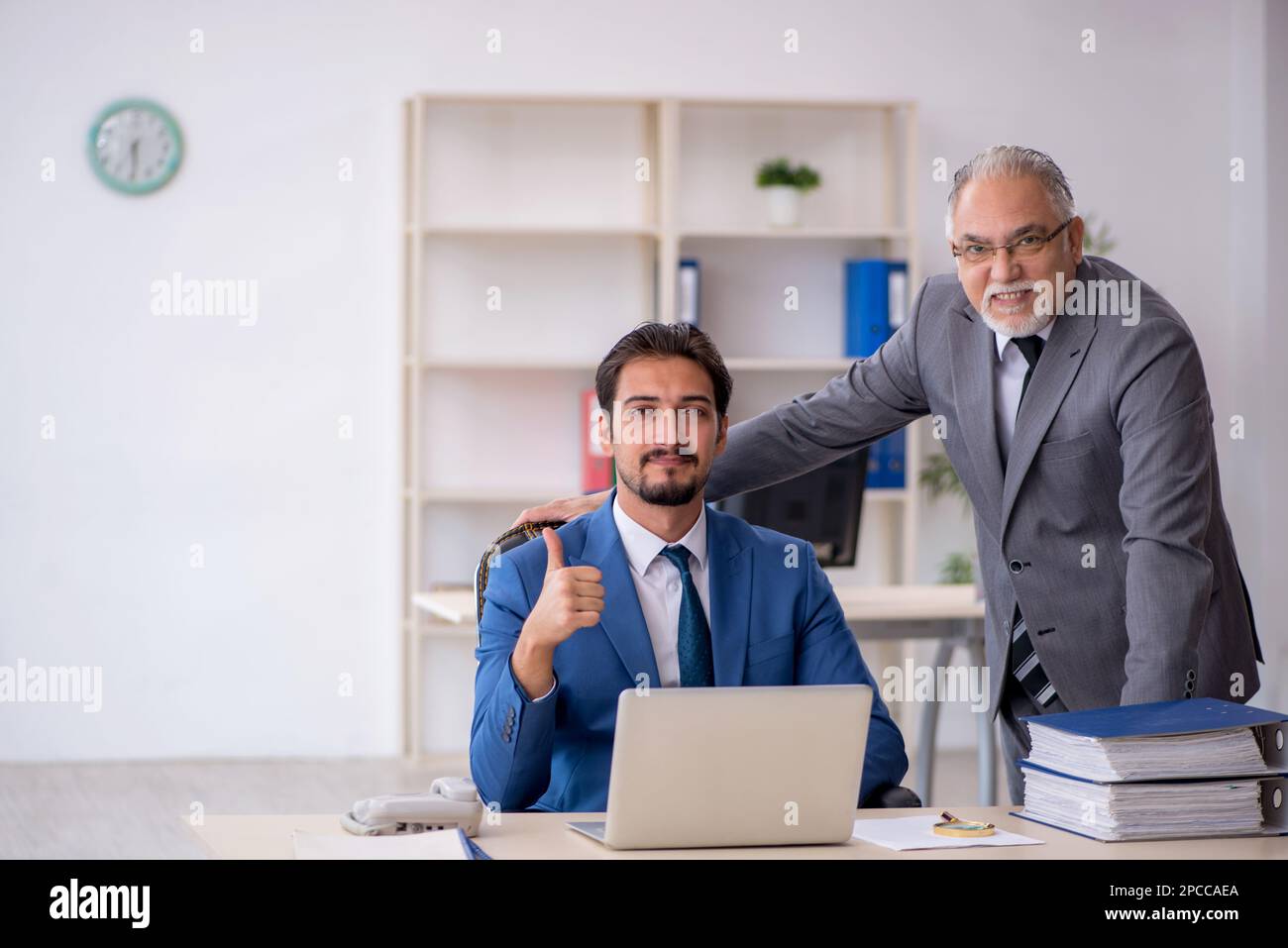 Old boss and young employee working at workplace Stock Photo - Alamy