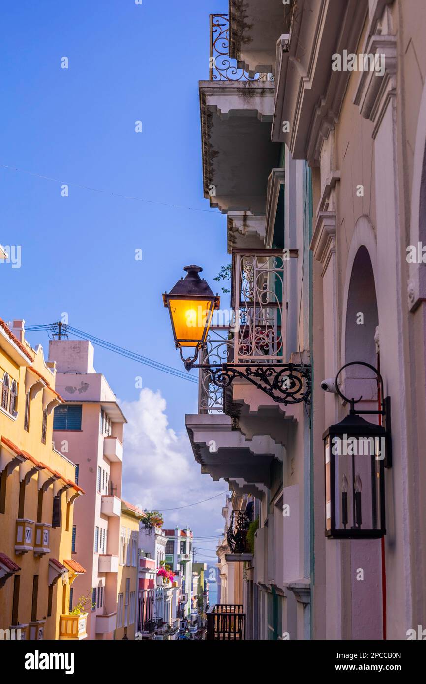 A bustling city street with vibrant yellow buildings and street lamps ...