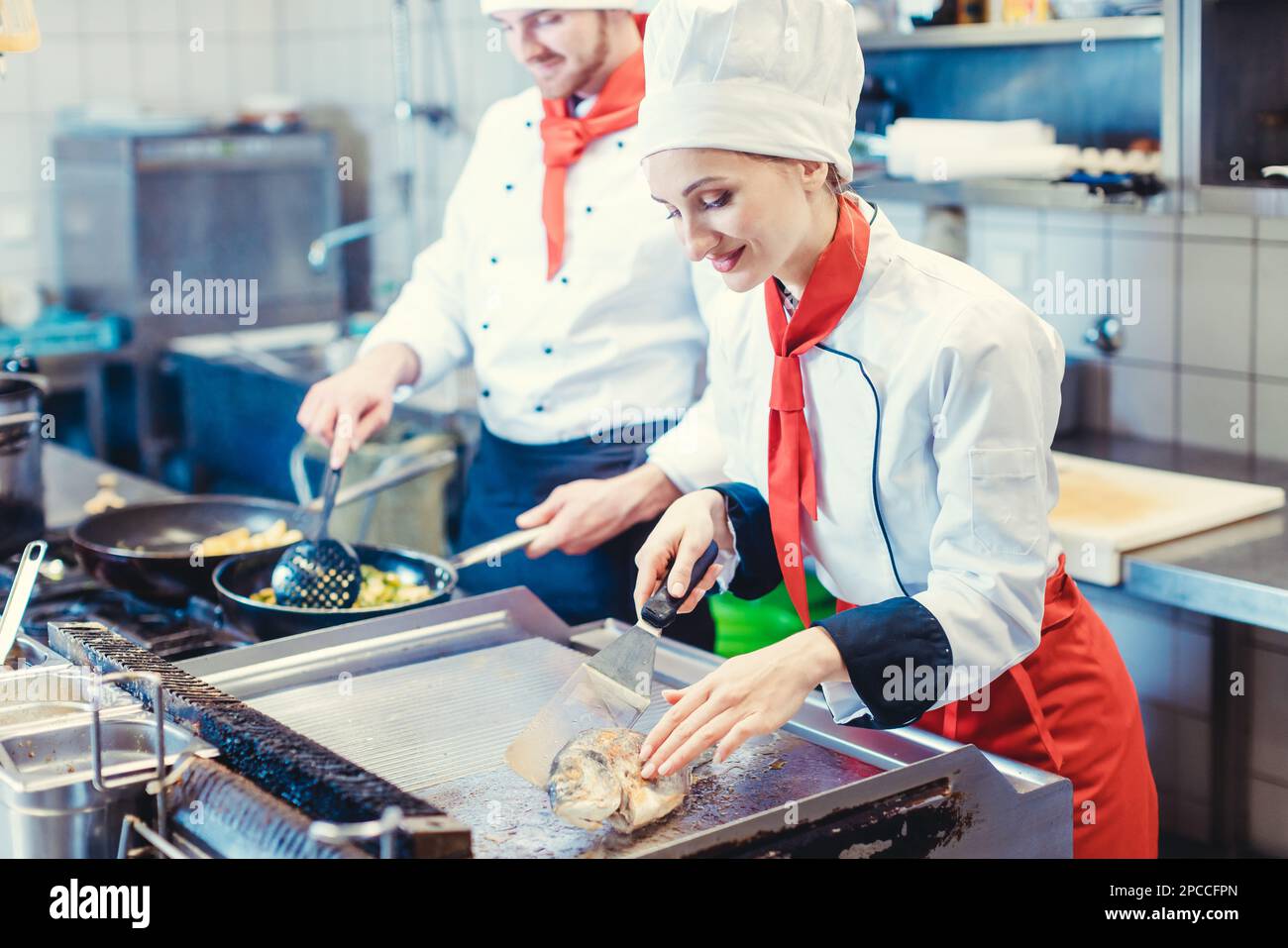 Chef woman and man cooking together in a restaurant kitchen Stock Photo ...