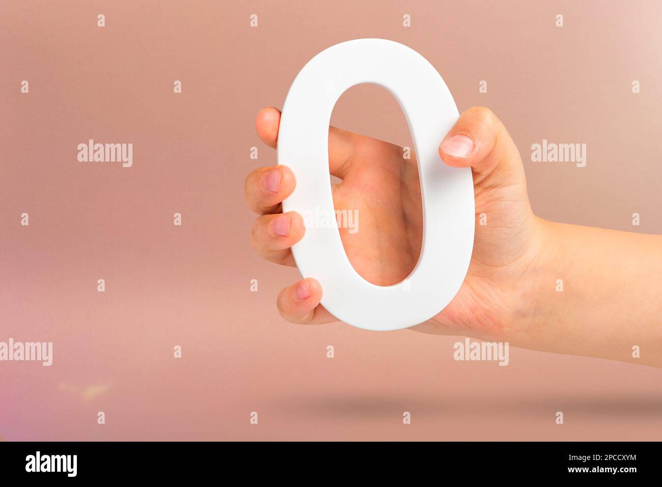 Numeral zero in hand. A hand holds a white number zero on a red ...