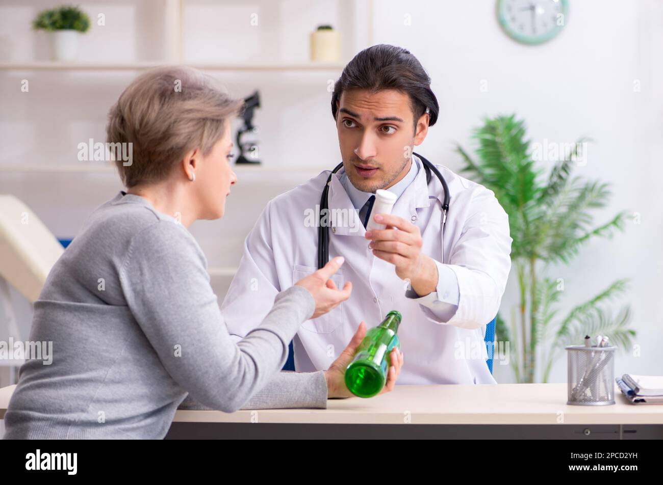 The female alcoholic visiting young male doctor Stock Photo - Alamy