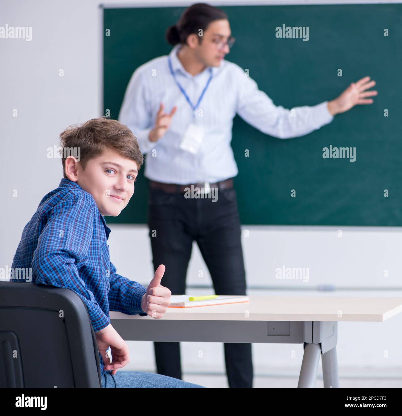 The young male teacher and boy in the classroom Stock Photo - Alamy