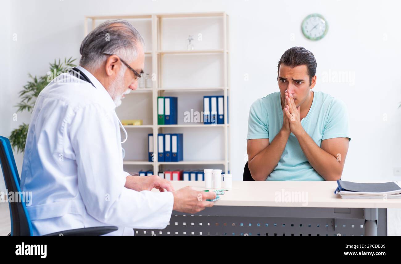 The young man visiting old male doctor Stock Photo - Alamy