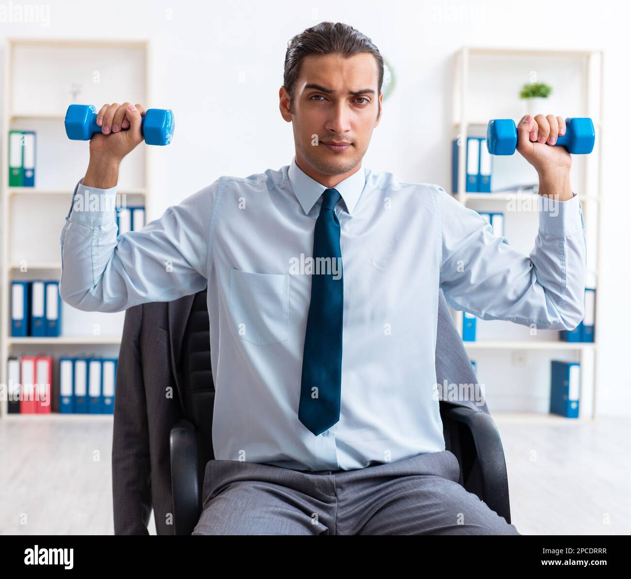 The young handsome employee doing sport exercises at workplace Stock ...