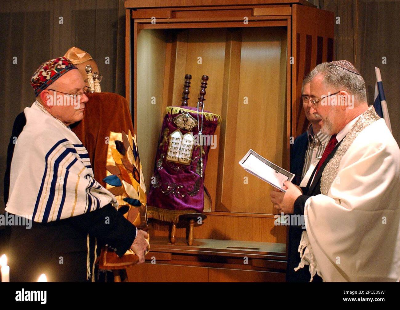 Rabbi Burt E. Schuman, left, holds the Torah as he listens to Rabbi Uri ...