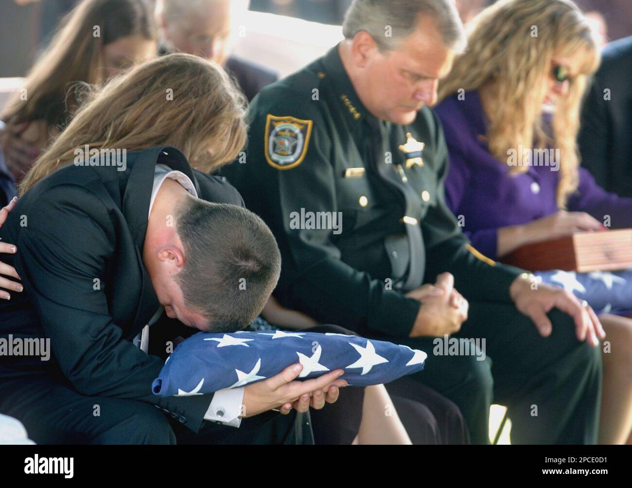 Christopher Daniels Jr., puts his face in the folded flag from his ...