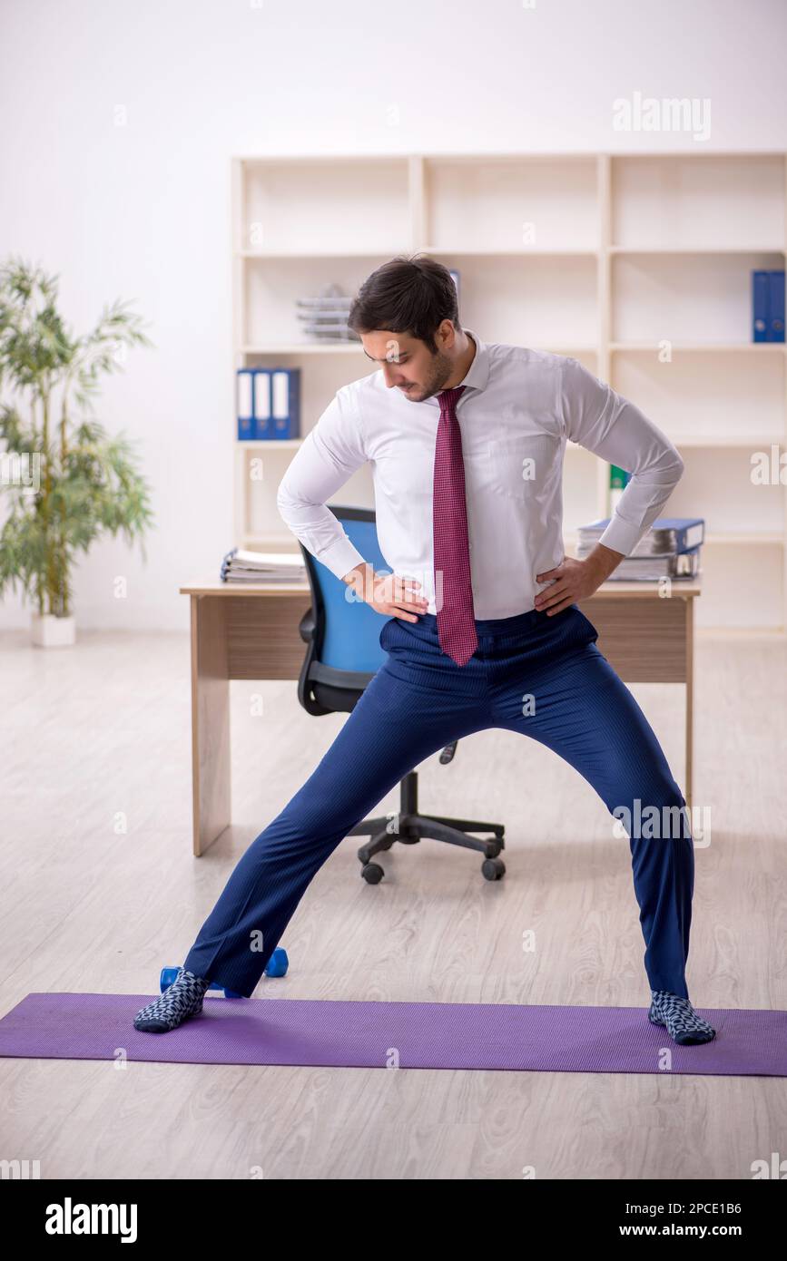 Young employee doing sport exercises during break Stock Photo - Alamy