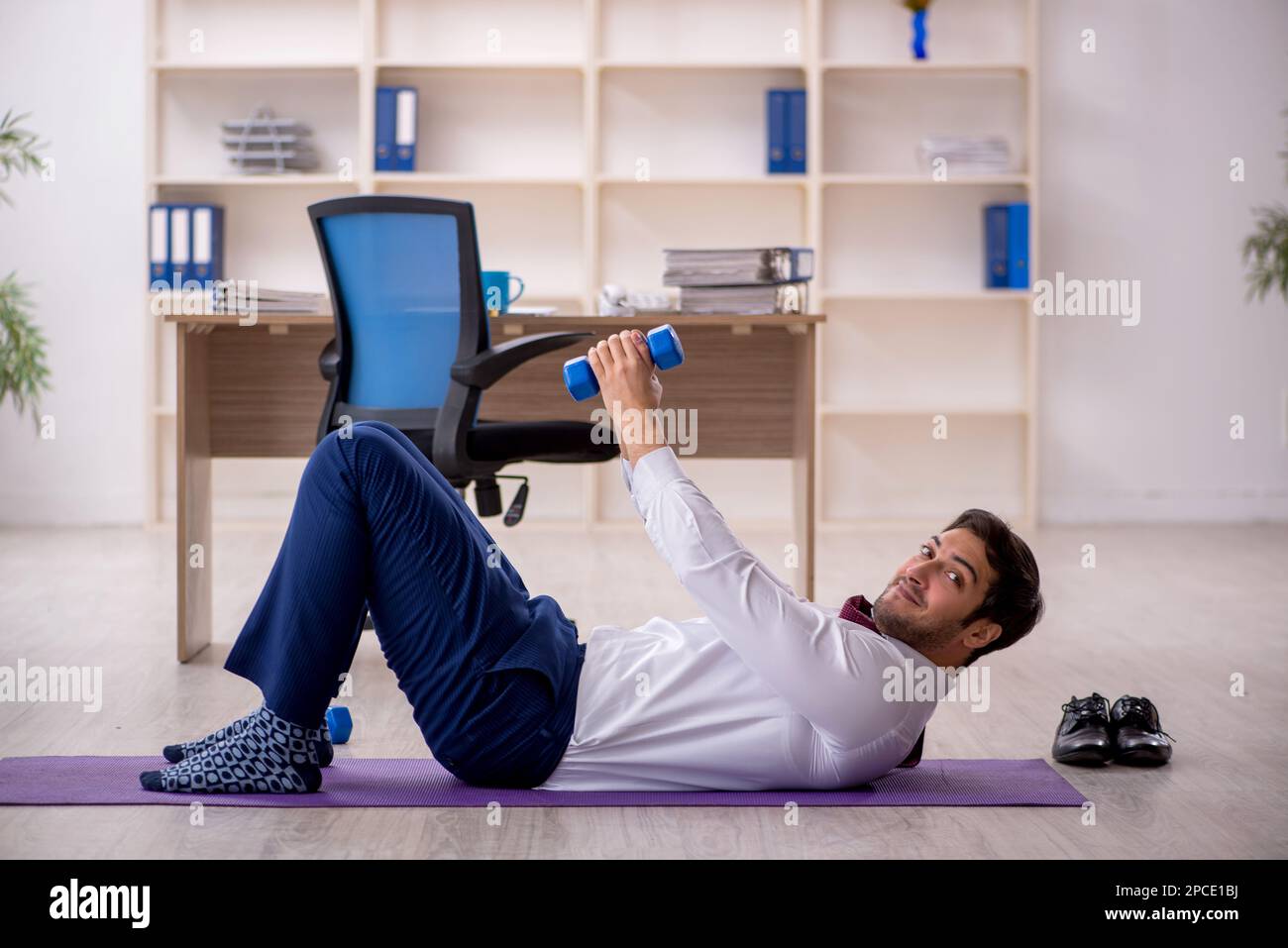 Young employee doing sport exercises during break Stock Photo - Alamy