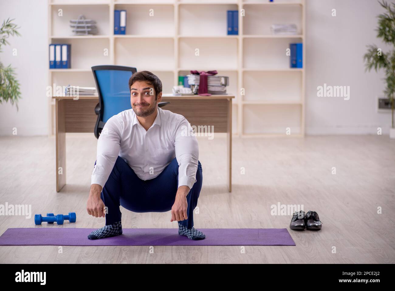 Young employee doing sport exercises during break Stock Photo - Alamy