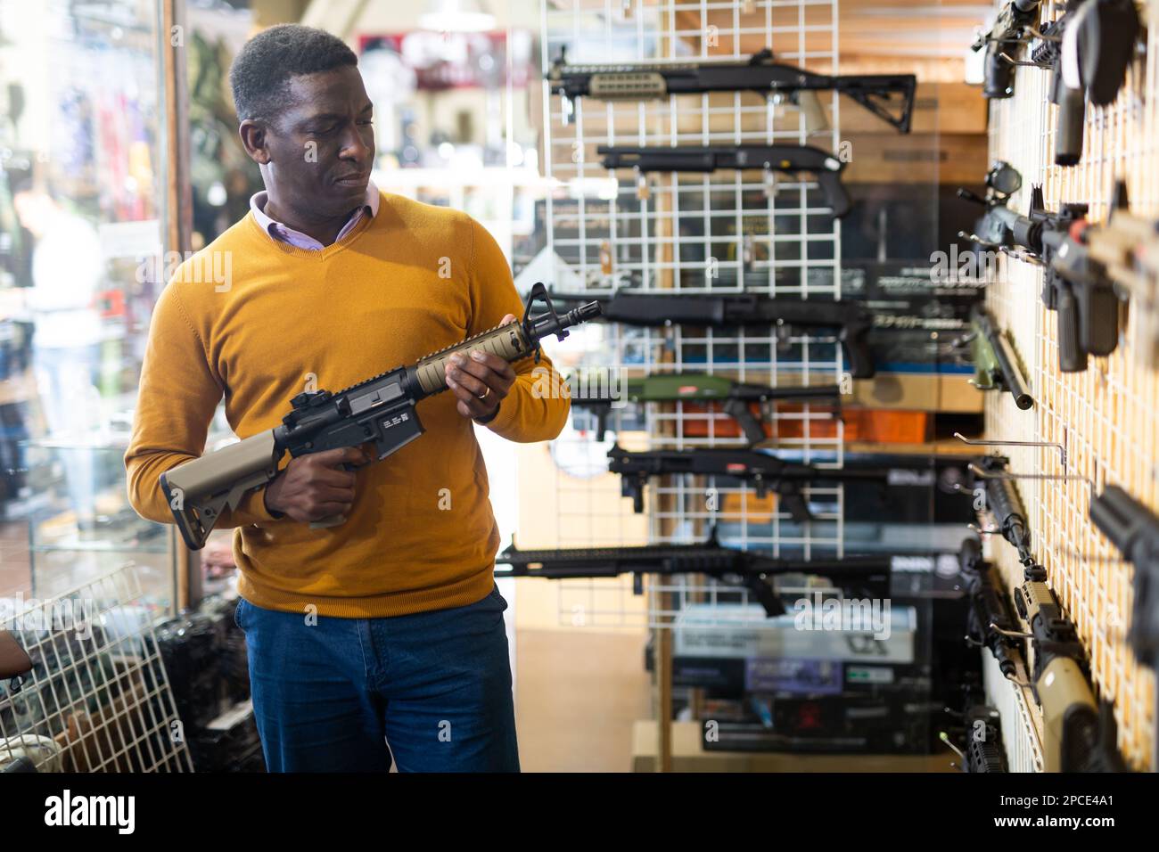 Man selecting assault rifle in weapon shop Stock Photo - Alamy