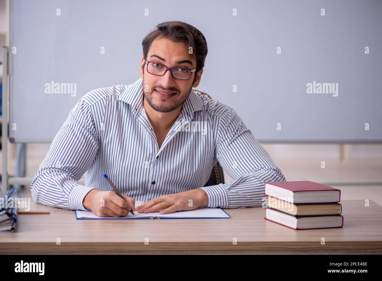 Young teacher sitting in the classroom Stock Photo - Alamy