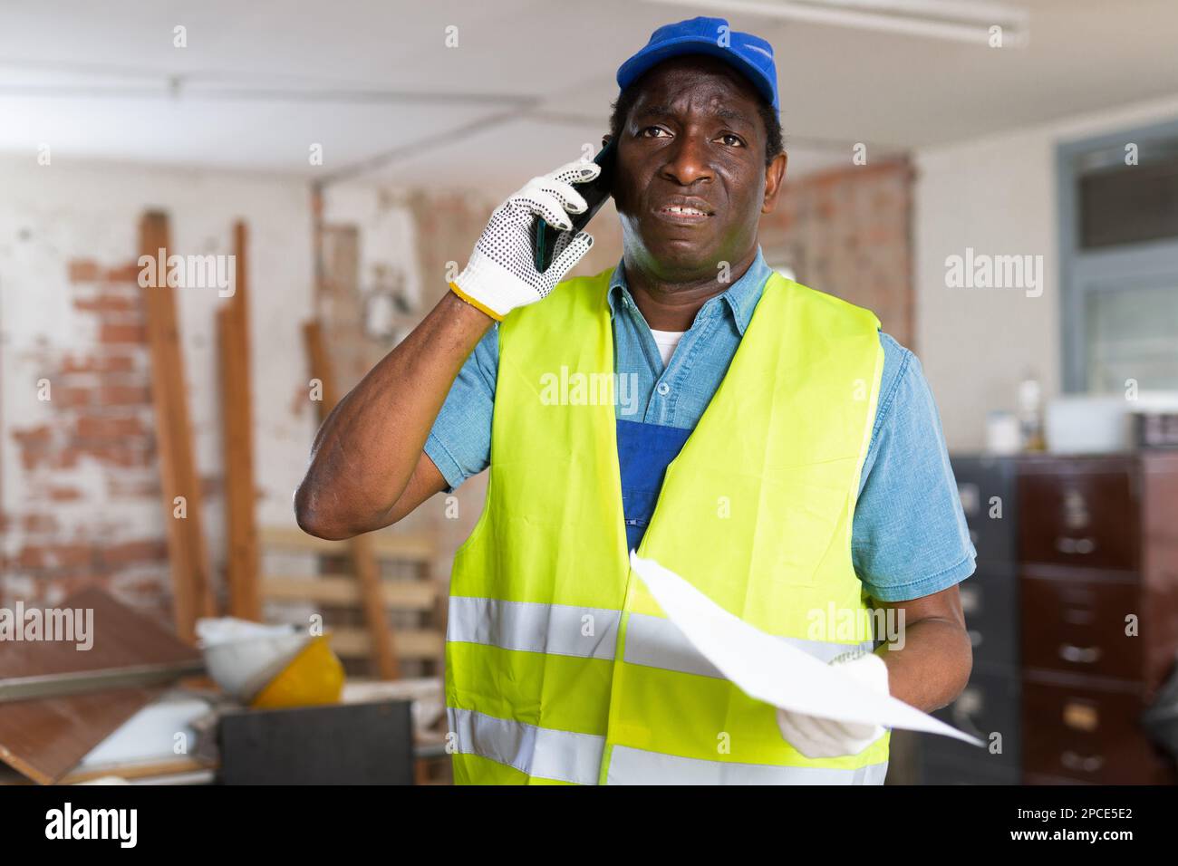 African american foreman holding list of tasks and talking on phone ...
