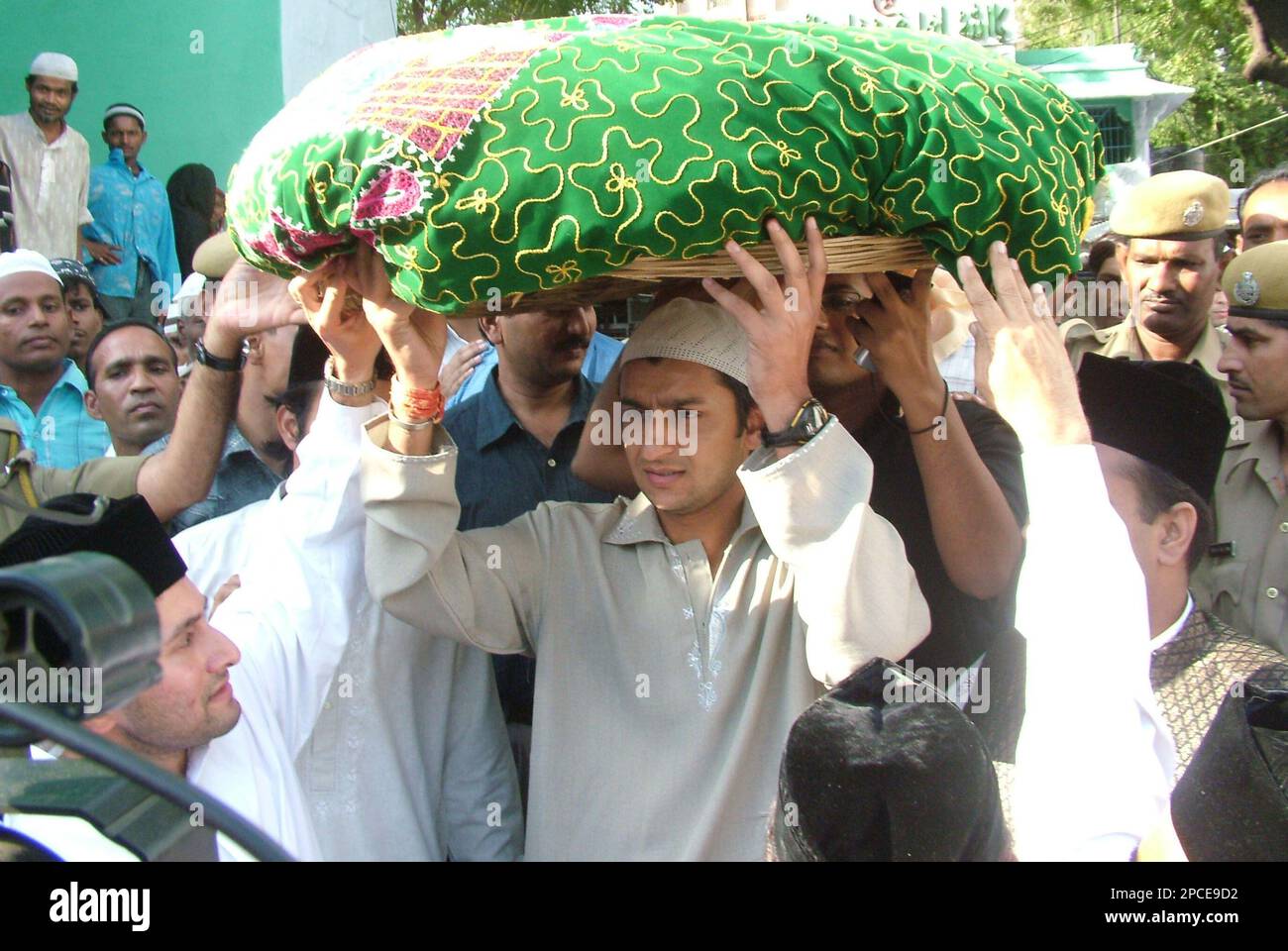 Pakistani cricketer Faisal Iqbal carries offerings of fresh roses and ...