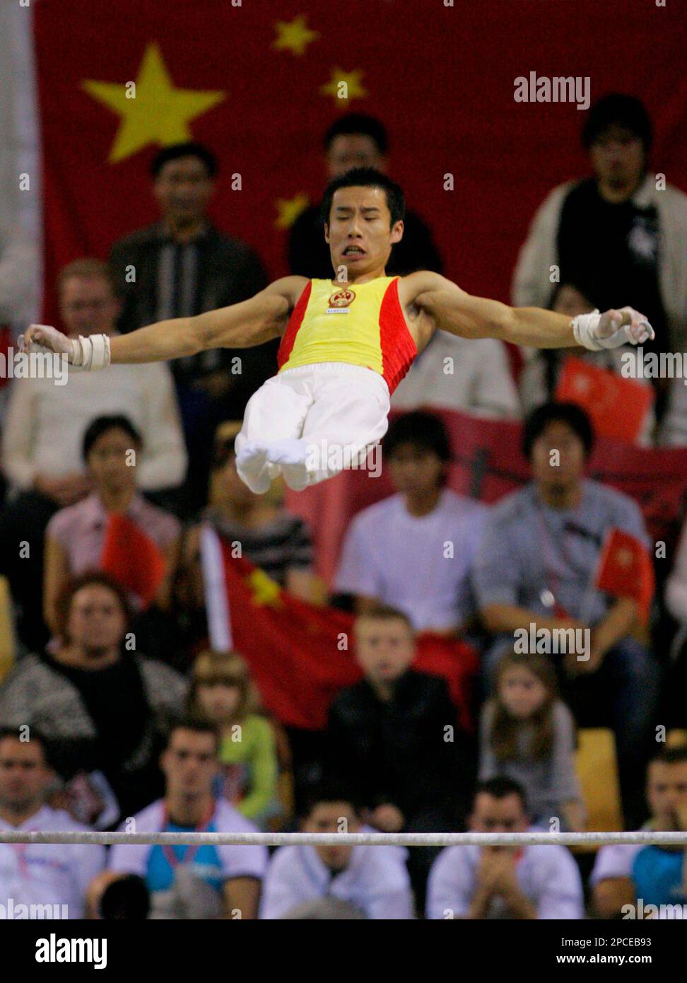 Xiao Qin of China competes on the horizontal bar as a Chinese flag can ...