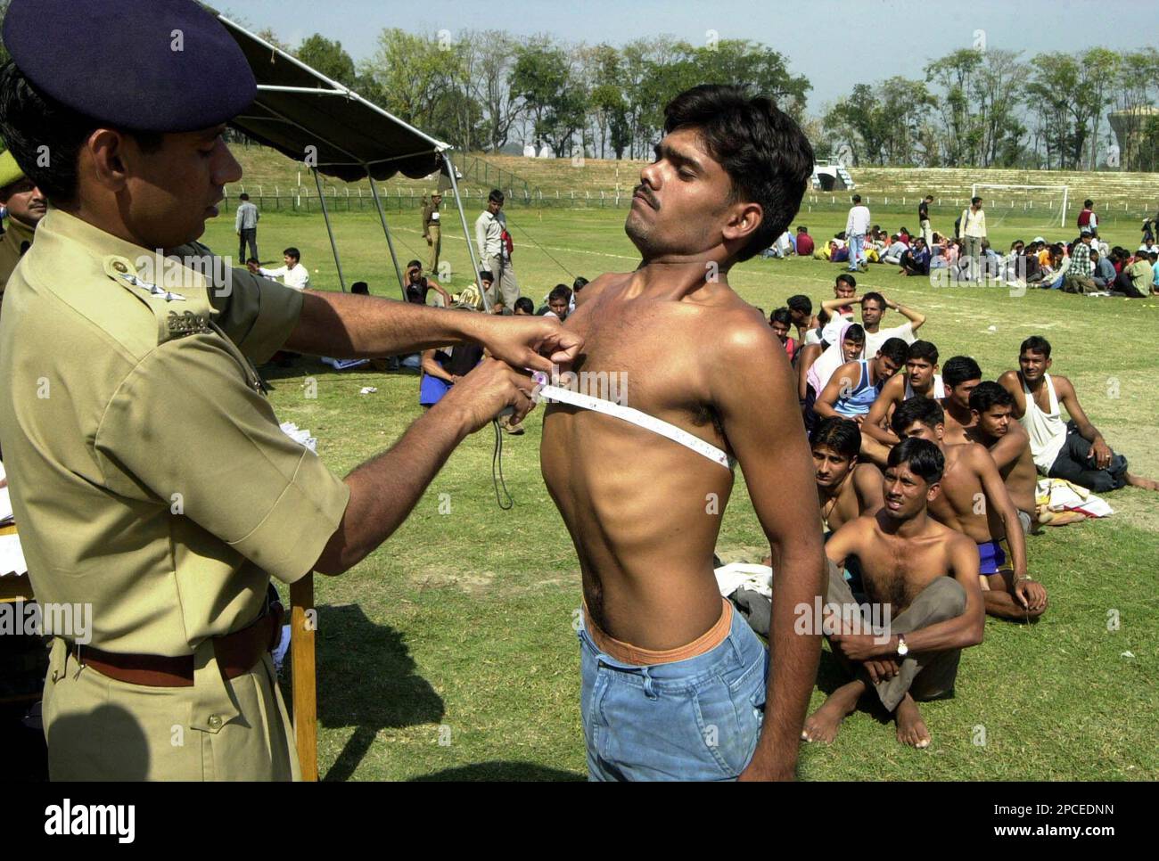 A paramilitary officer measures the chest of a probable recruit, as ...