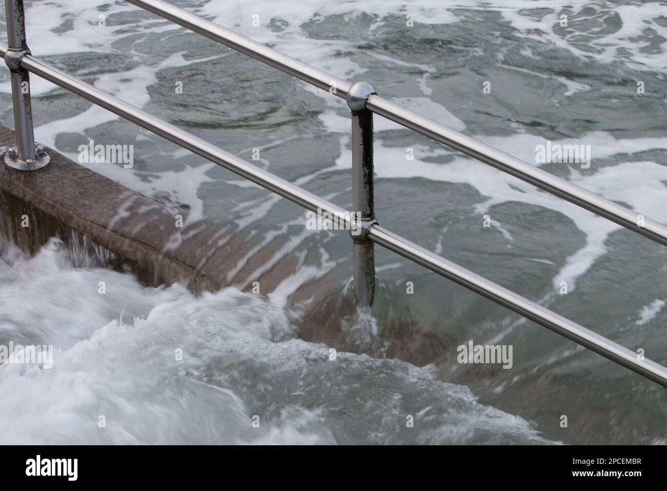Waves crashing over steps and railings at high tide. Bristol Channel ...