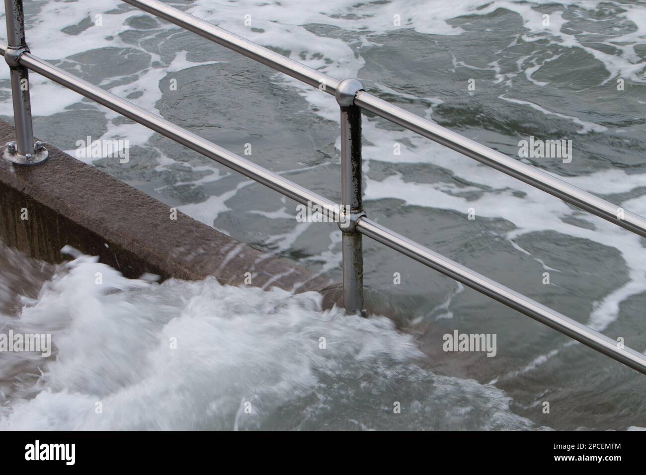 Waves crashing over steps and railings at high tide. Bristol Channel ...