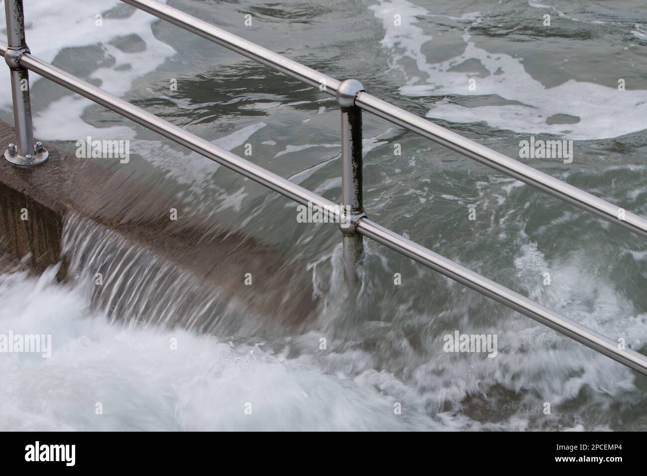 Waves crashing over steps and railings at high tide. Bristol Channel ...