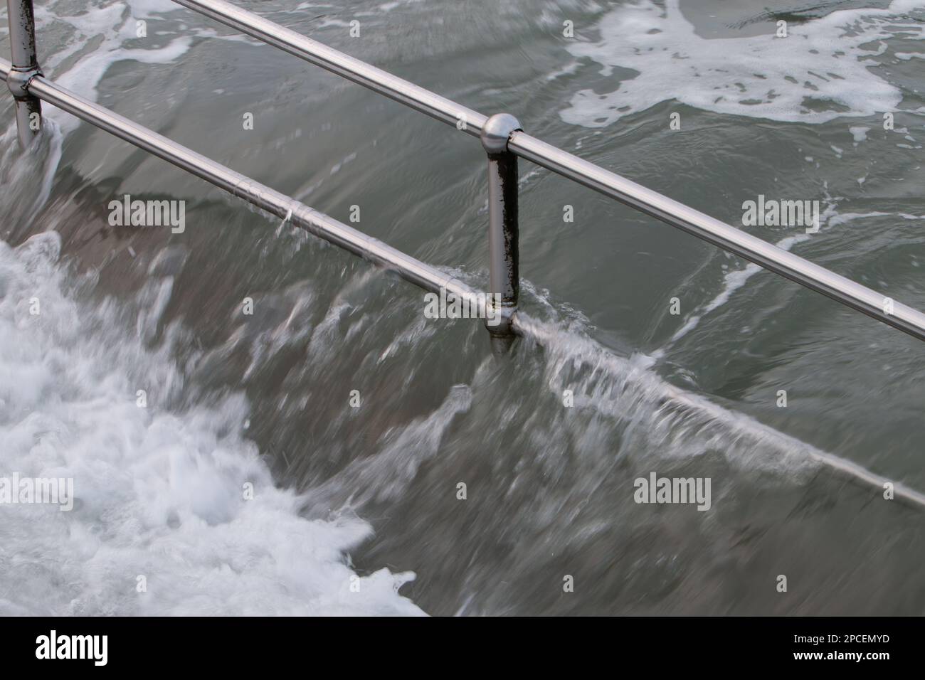 Waves crashing over steps and railings at high tide. Bristol Channel ...
