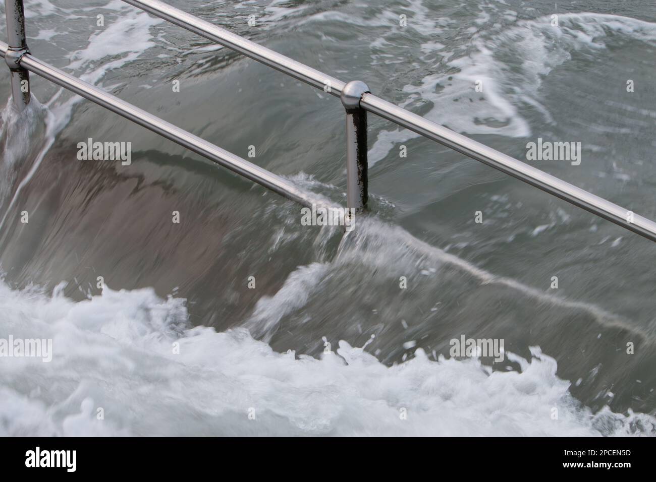 Waves crashing over steps and railings at high tide. Bristol Channel ...