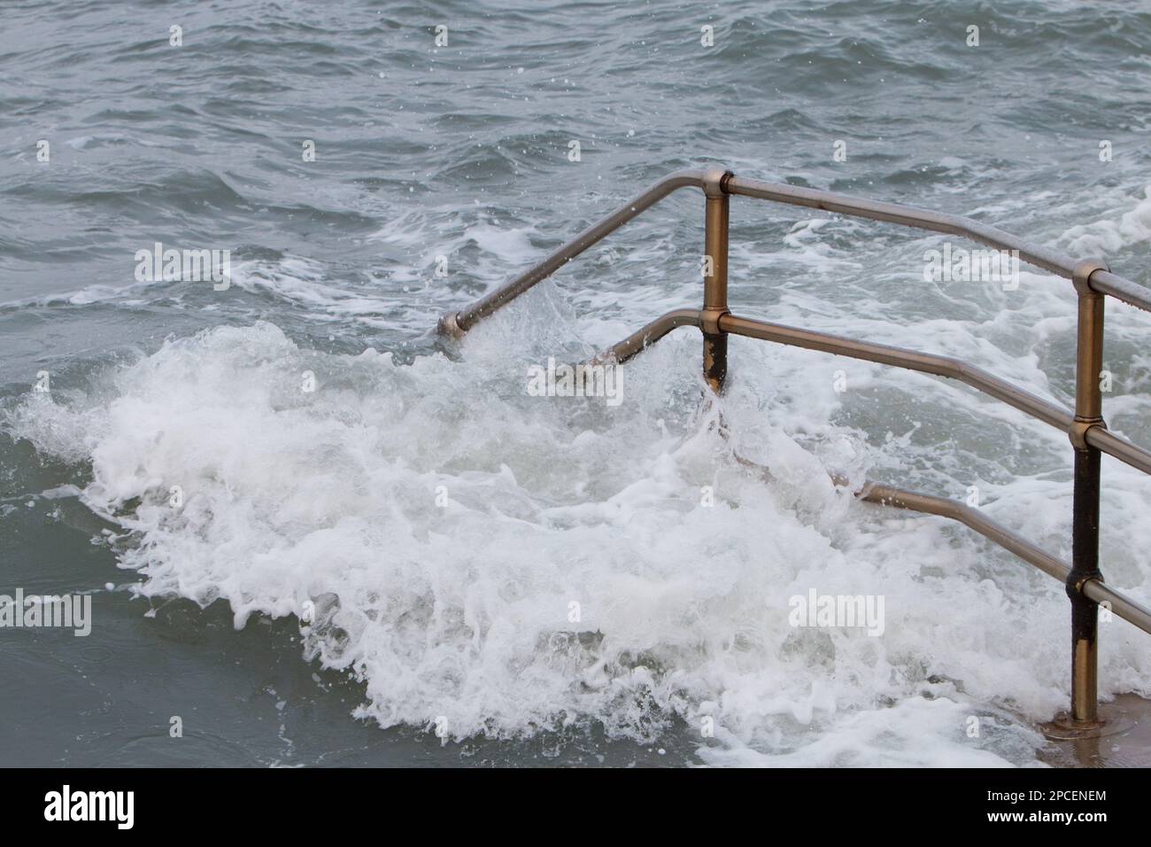 Waves crashing over steps and railings at high tide. Bristol Channel ...