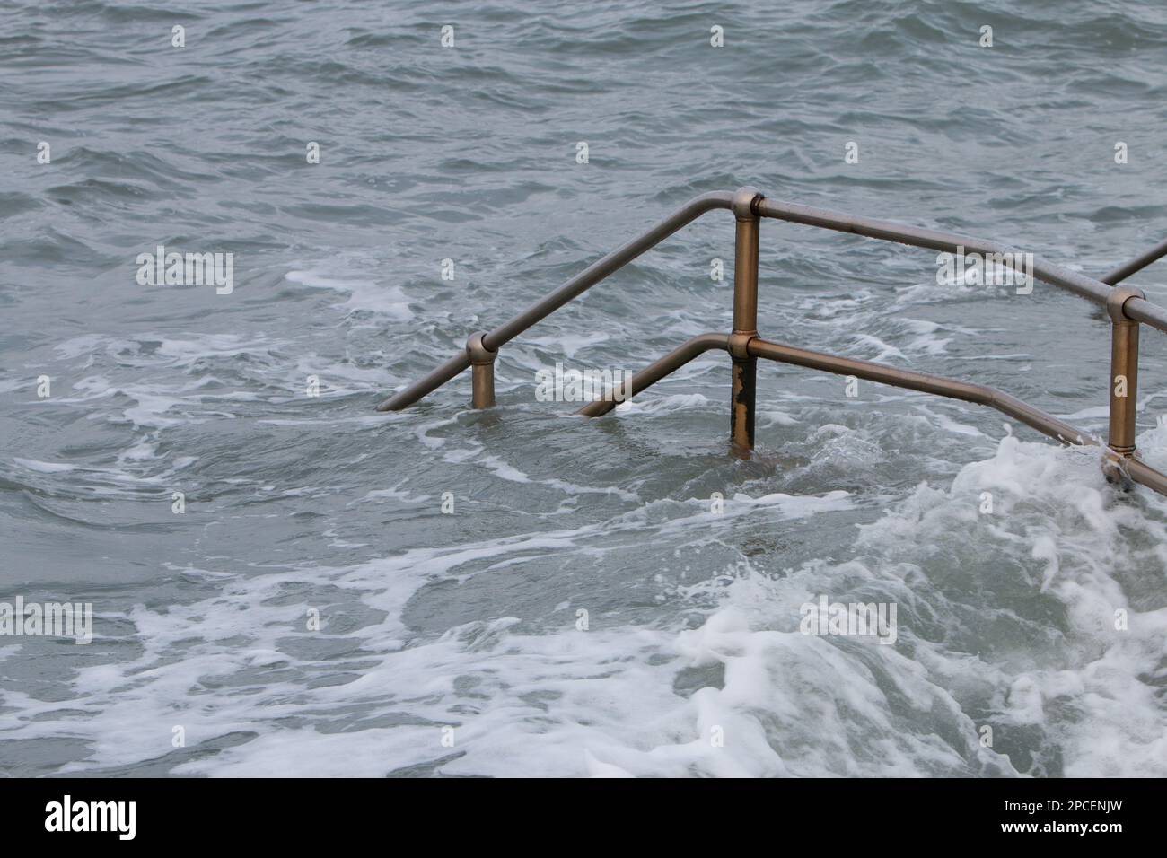 Waves crashing over steps and railings at high tide. Bristol Channel ...