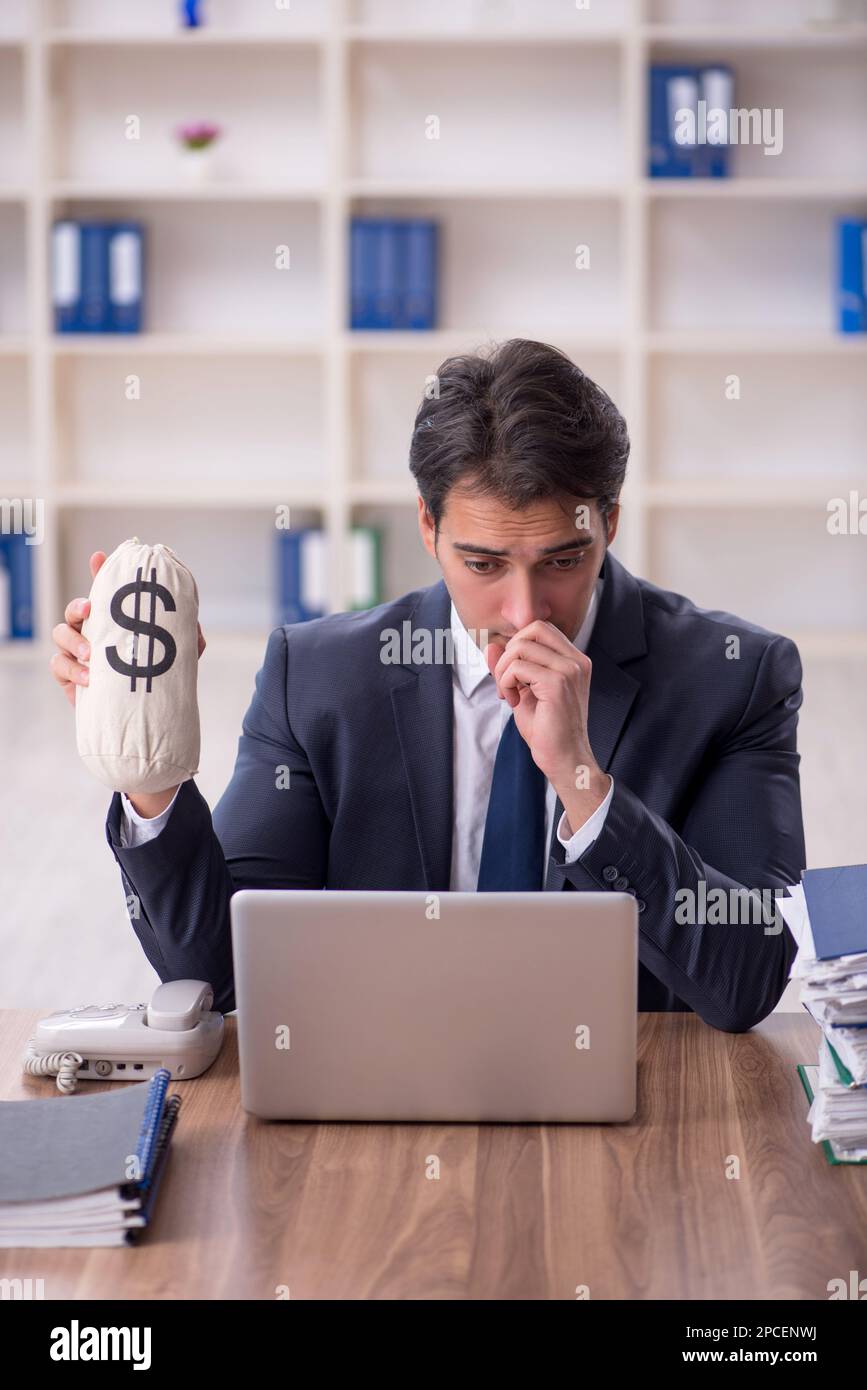 Young employee holding moneybag at workplace Stock Photo - Alamy