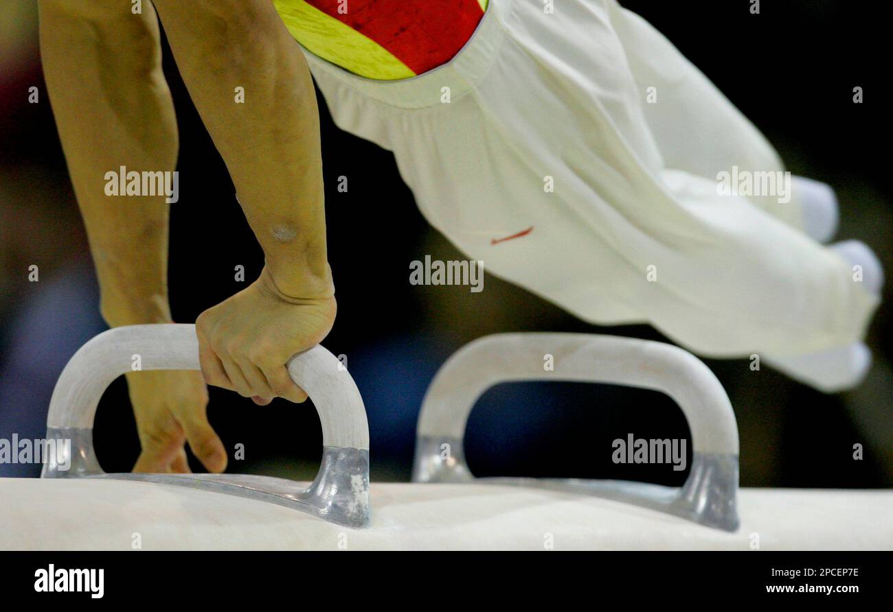 A Chinese competitor's hand grips as he performs on the pommel horse ...