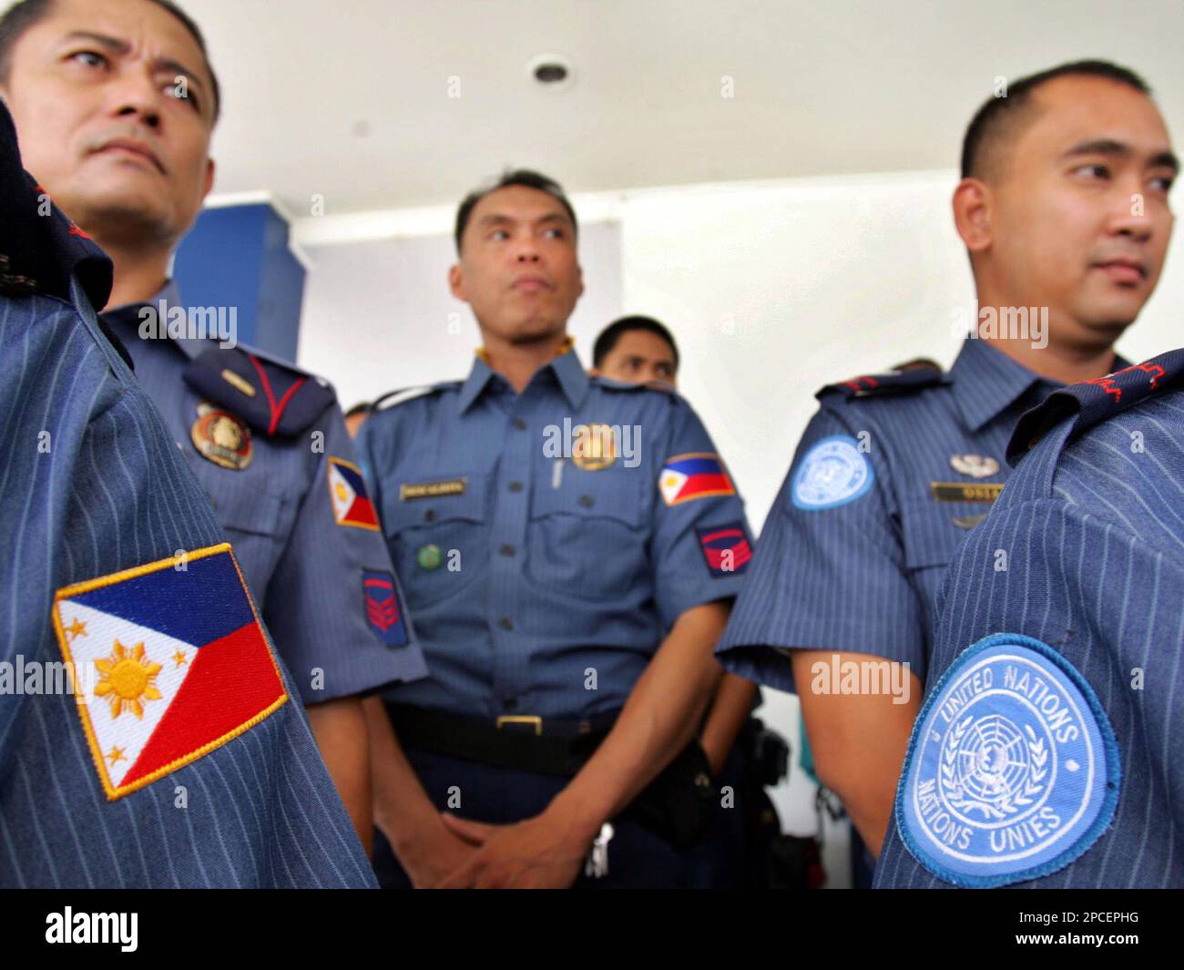 Filipino police officers listen during their final briefing before ...