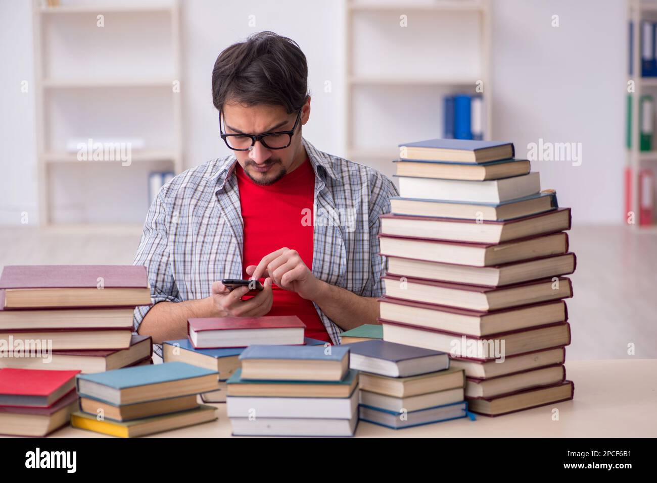 Young student and too many books in the classroom Stock Photo - Alamy