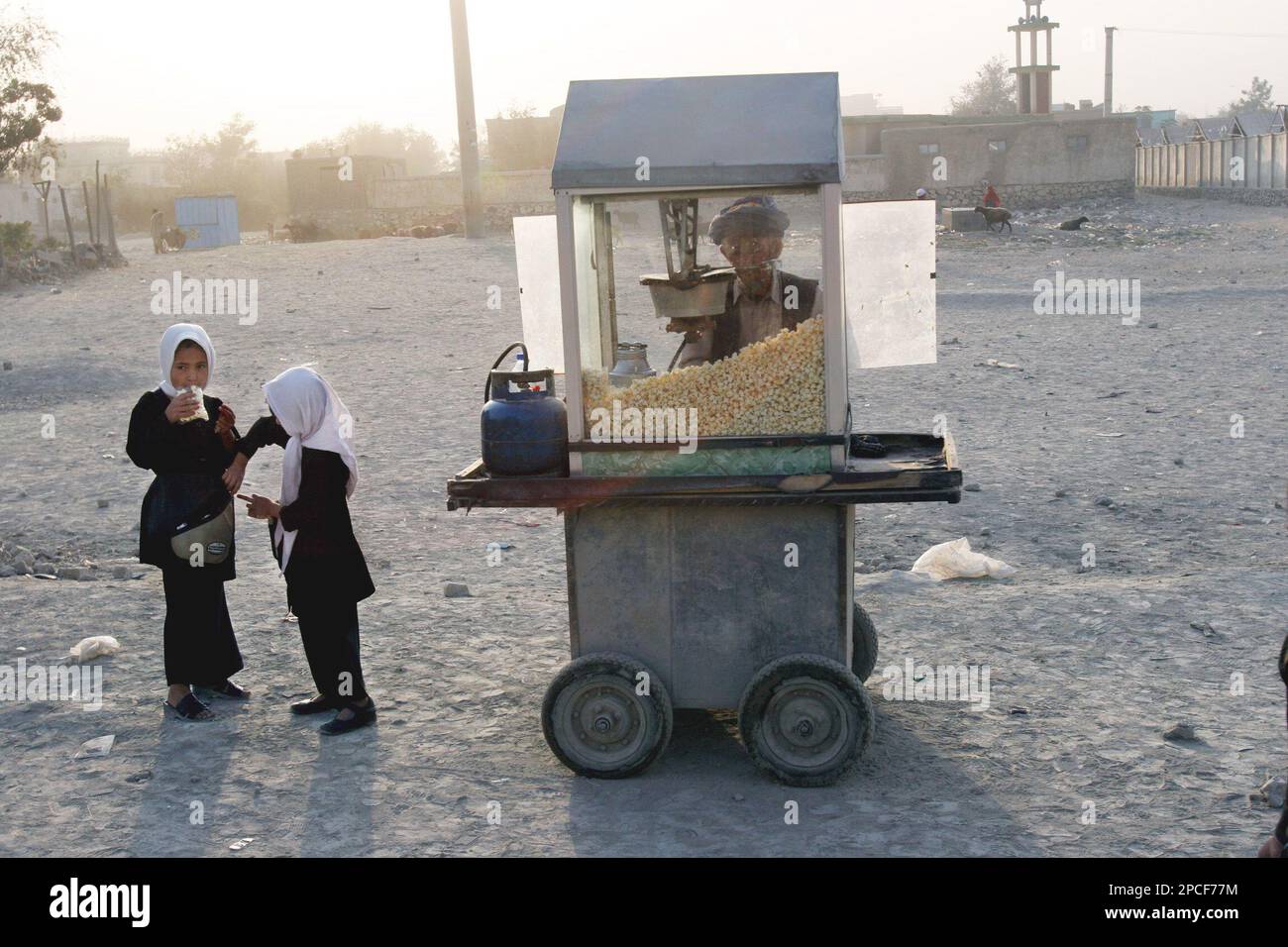 Schoolgirls buy popcorn at a stall before entering their school in ...