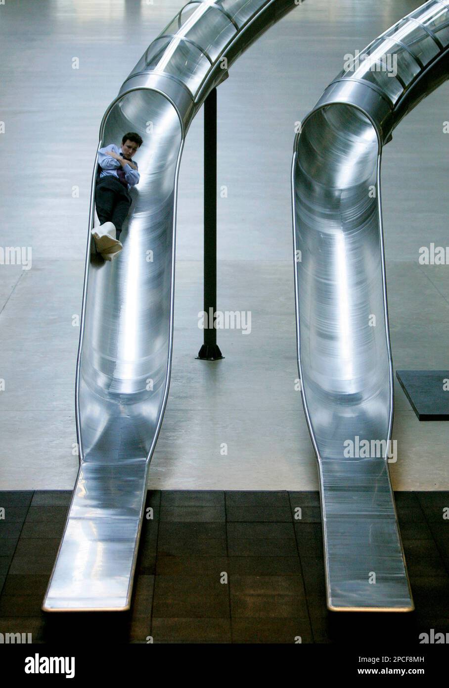 A man travels down a slide chute which forms part of an art exhibit ...