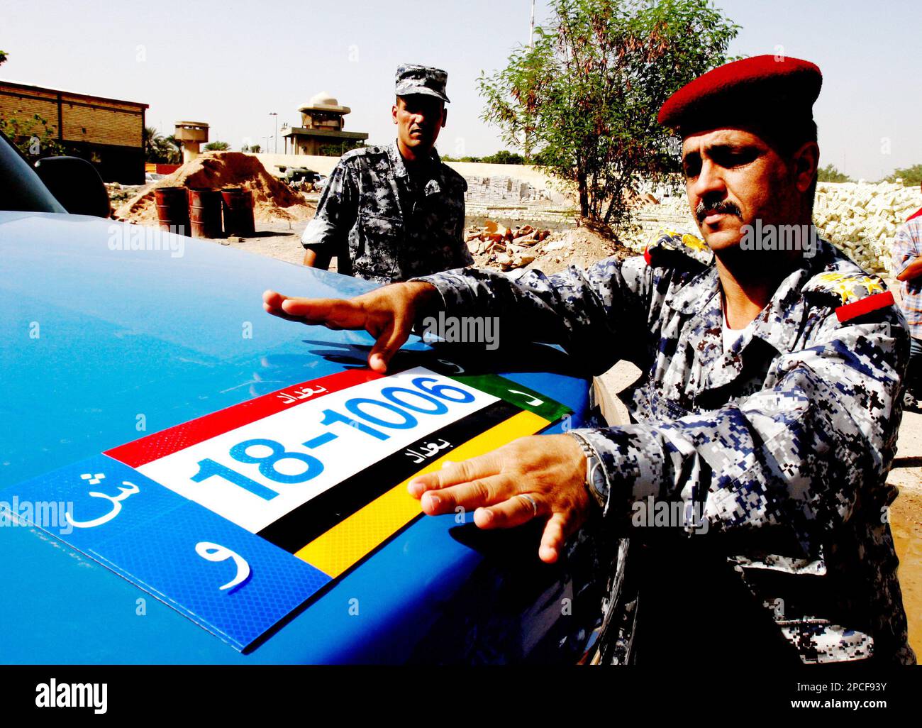 An Iraqi policeman fixes newly designed licence plates on a patrol car ...