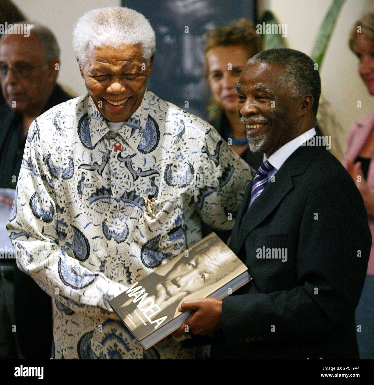 Former South African President Nelson Mandela gives South African President Thabo Mbeki a copy ...