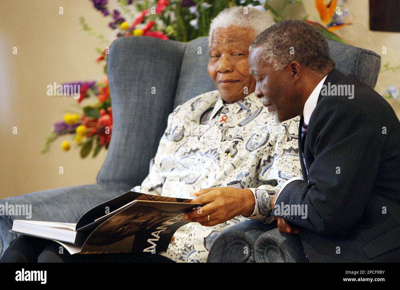 Former South African President Nelson Mandela shows South African President Thabo Mbeki a copy ...