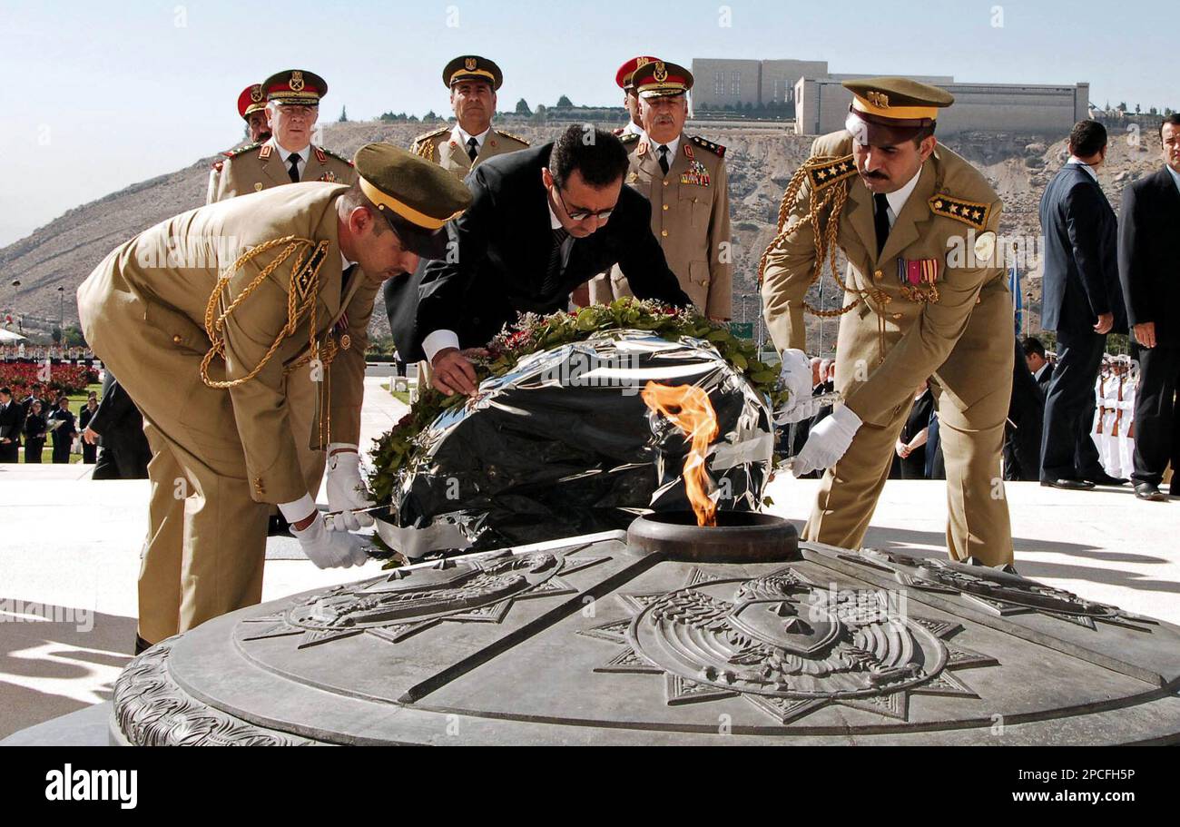 Syrian President Bashar Assad, center, lays a wreath of flowers on the ...