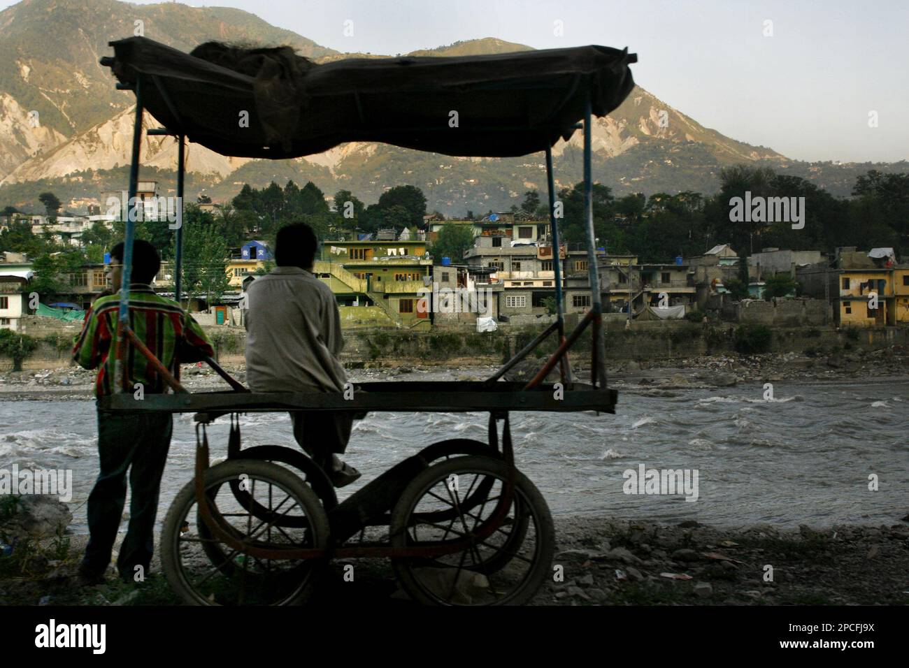 Pakistani boys sit on a market cart along the river in Muzaffarabad in ...