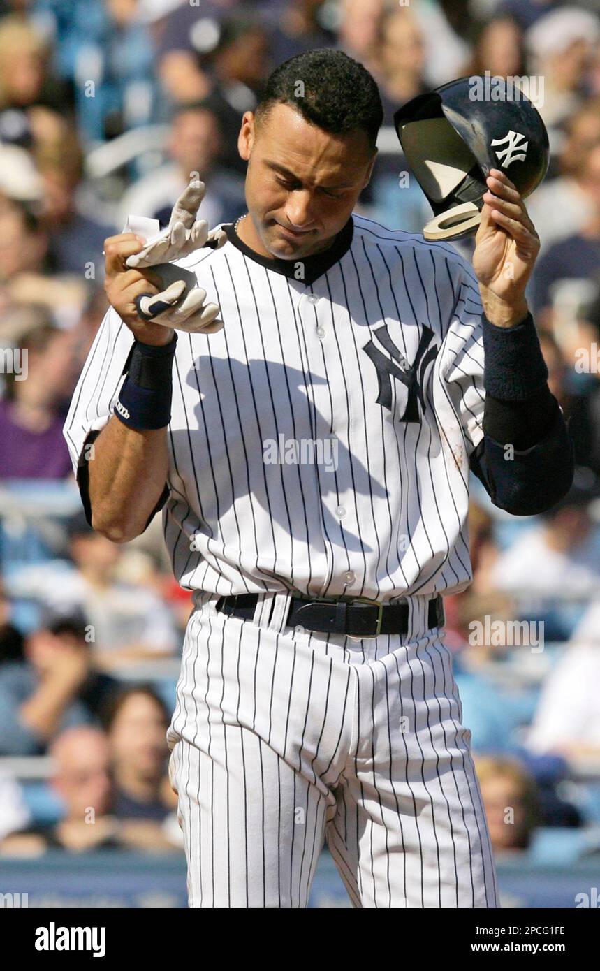 New York Yankees Derek Jeter tosses his batting gloves into his helmet ...
